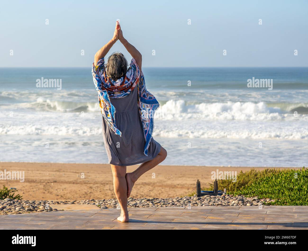 Woman performing yoga Tree pose Vrikshasanayoga, Atlantic Ocean Morocco ...