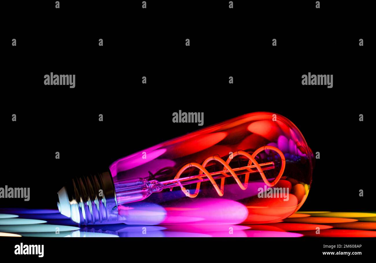 Colourful patterns reflect within a clear glass, oval shaped lightbulb ...