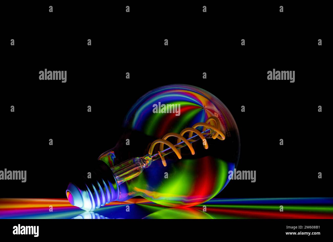 Colourful patterns reflect within a clear glass round shaped lightbulb ...