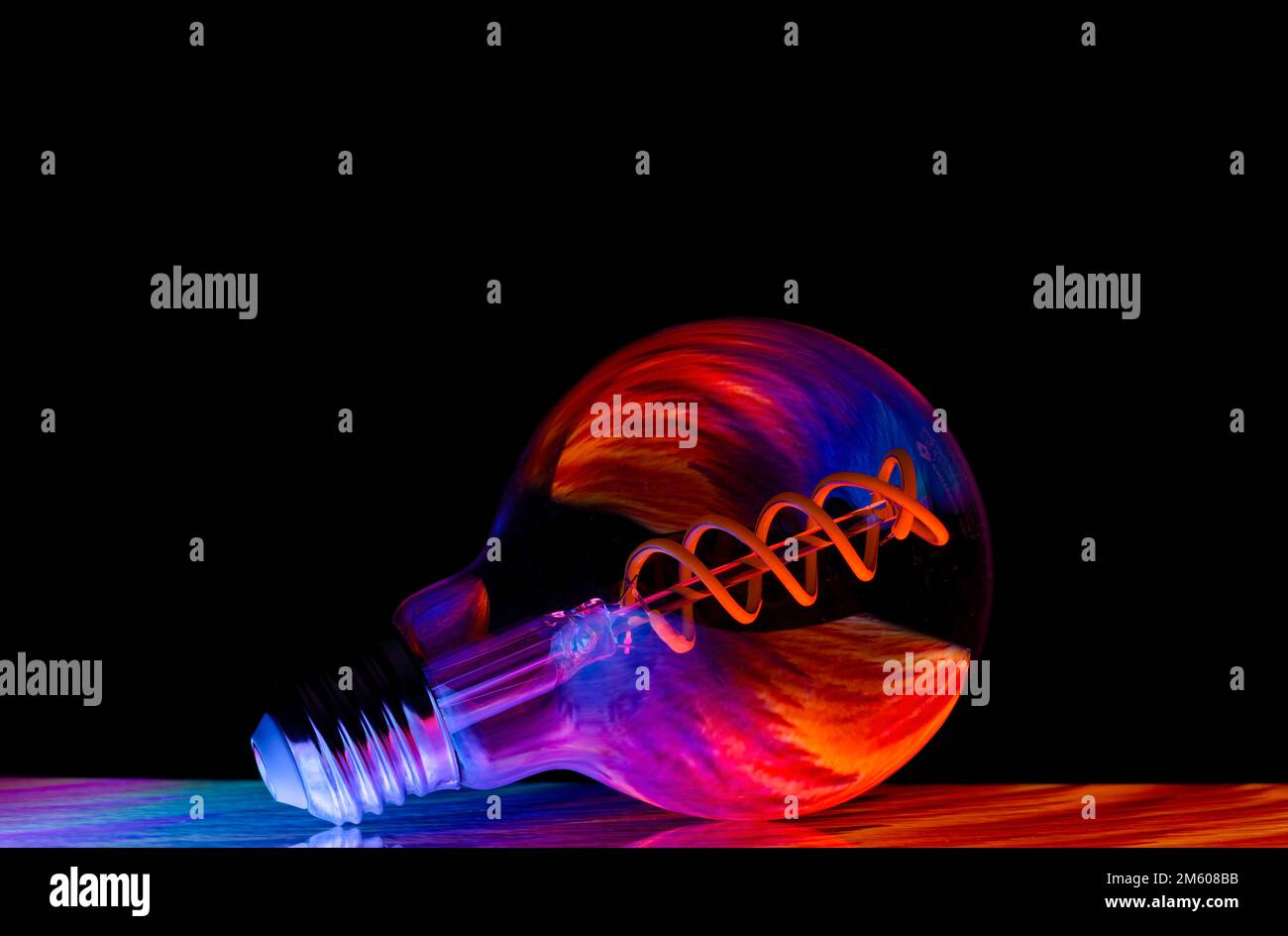 Colourful patterns reflect within a clear glass round shaped lightbulb ...