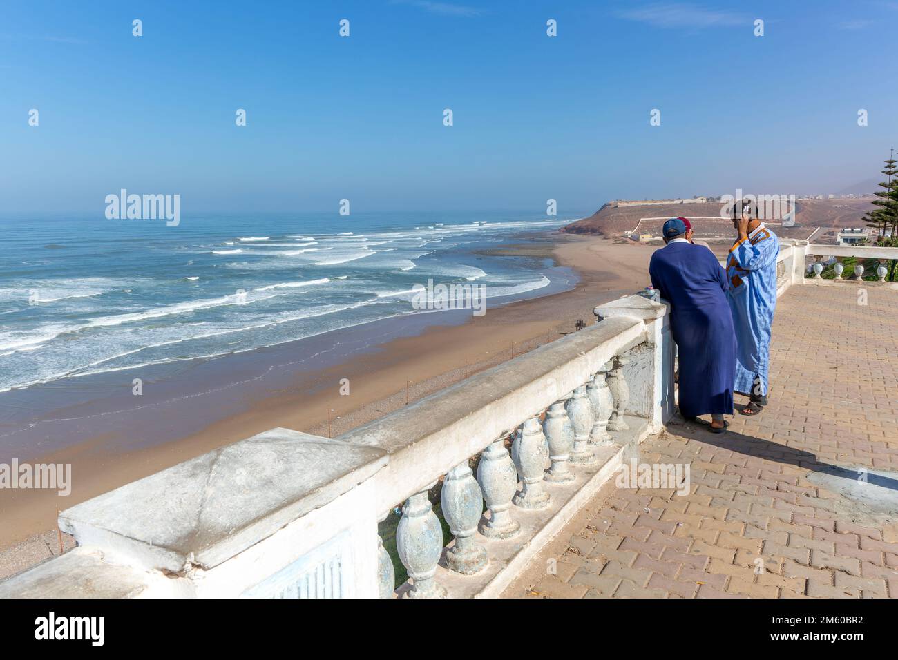 Moroccan men on coastal balustrade next to Atlantic Ocean, Sidi Ifni ...