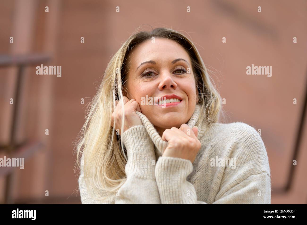 Attractive blonde middle aged woman with wind tousled hair has her ...