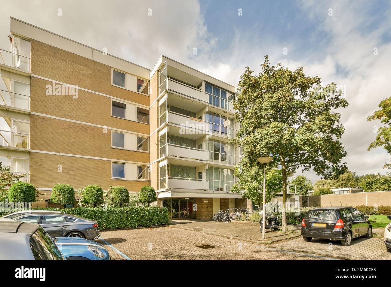 an apartment building with cars parked in the parking lot next to it ...