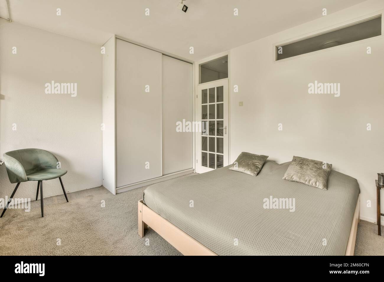 a bedroom with a bed, chair and closets in the back wall to the other ...