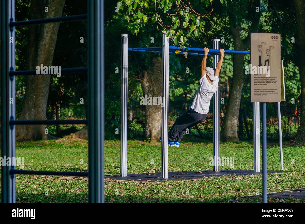 An elderly person using exercise equipment in the park on a sunny ...