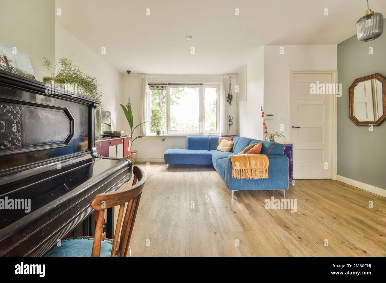 a living room with a piano in the middle and a blue couch on the other ...