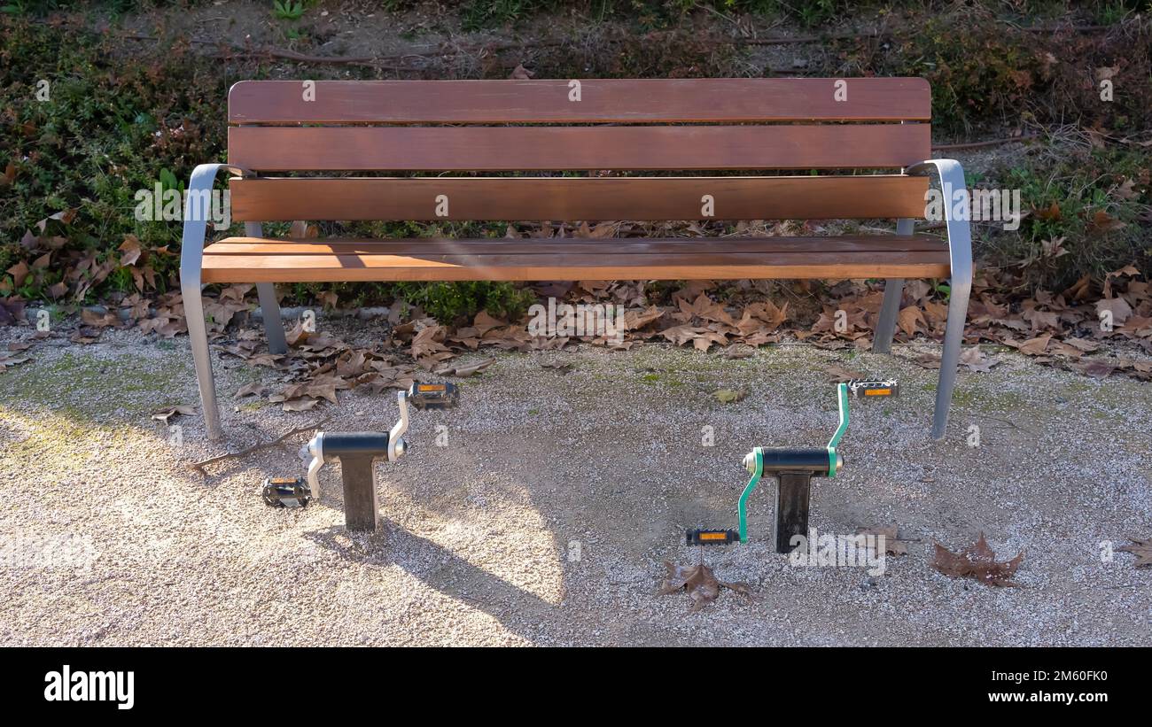 Wooden bench in a public park with pedals to exercise while enjoying ...
