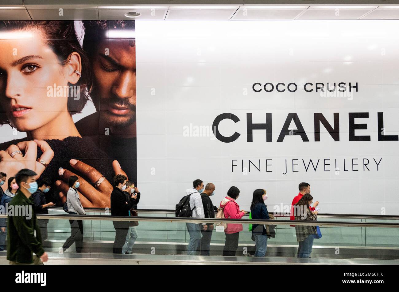 Commuters walk past a large commercial advertisement banner promoting ...