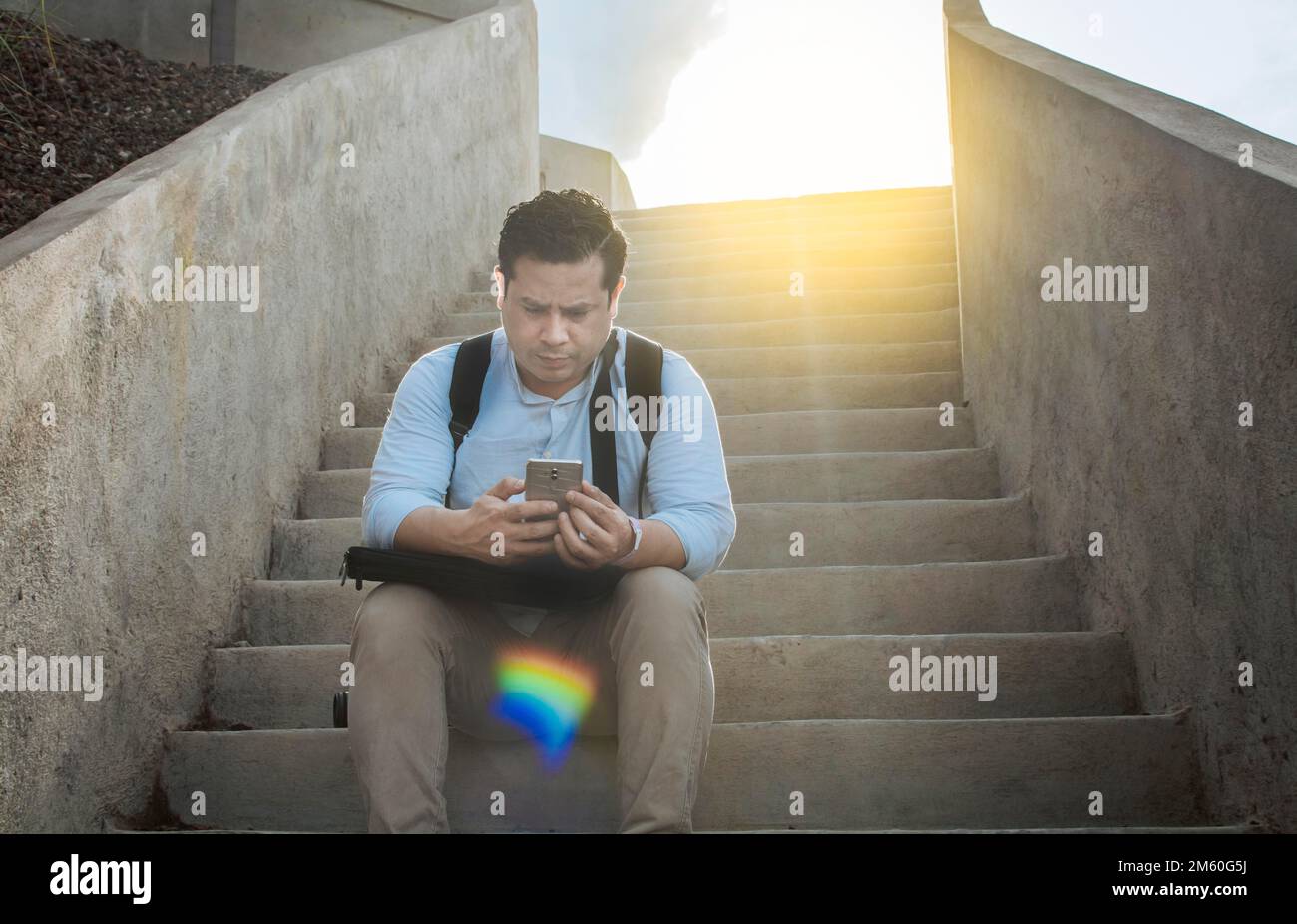 Handsome man sitting on stairs using smart phone, Front view of guy ...