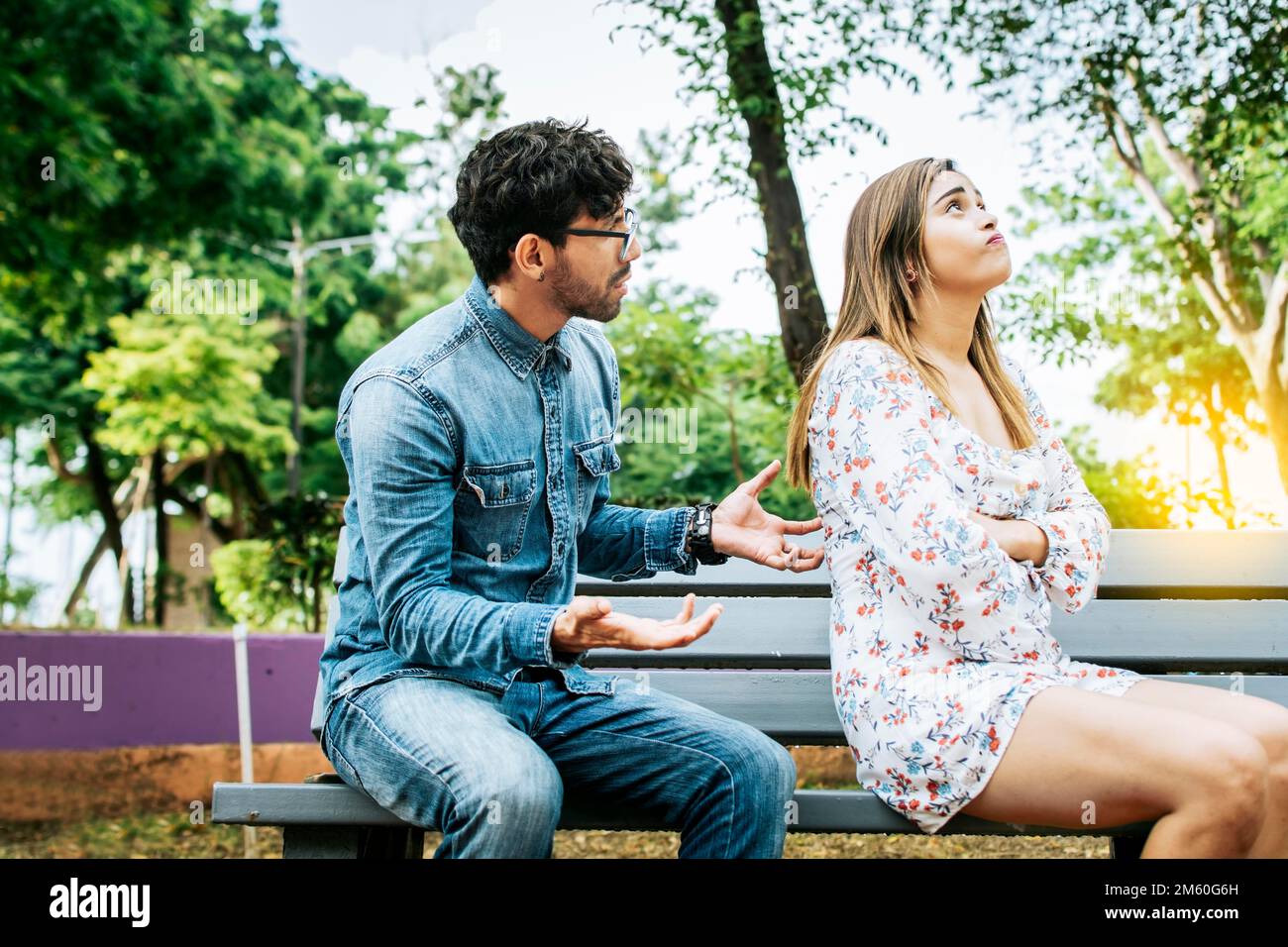 Upset couple arguing in a park. A young couple arguing sitting on a ...