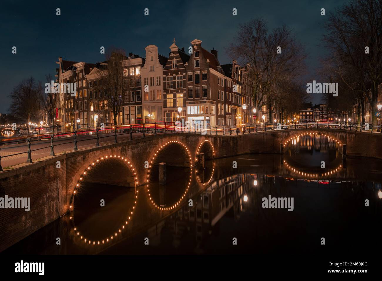 The beautiful canals of Amsterdam at night with glowing lights during ...