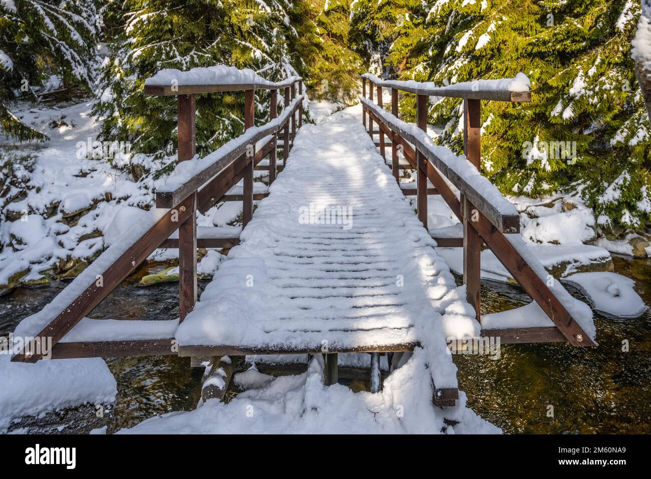 Small wooden footbridge covered by snow over icy mountain creek in ...
