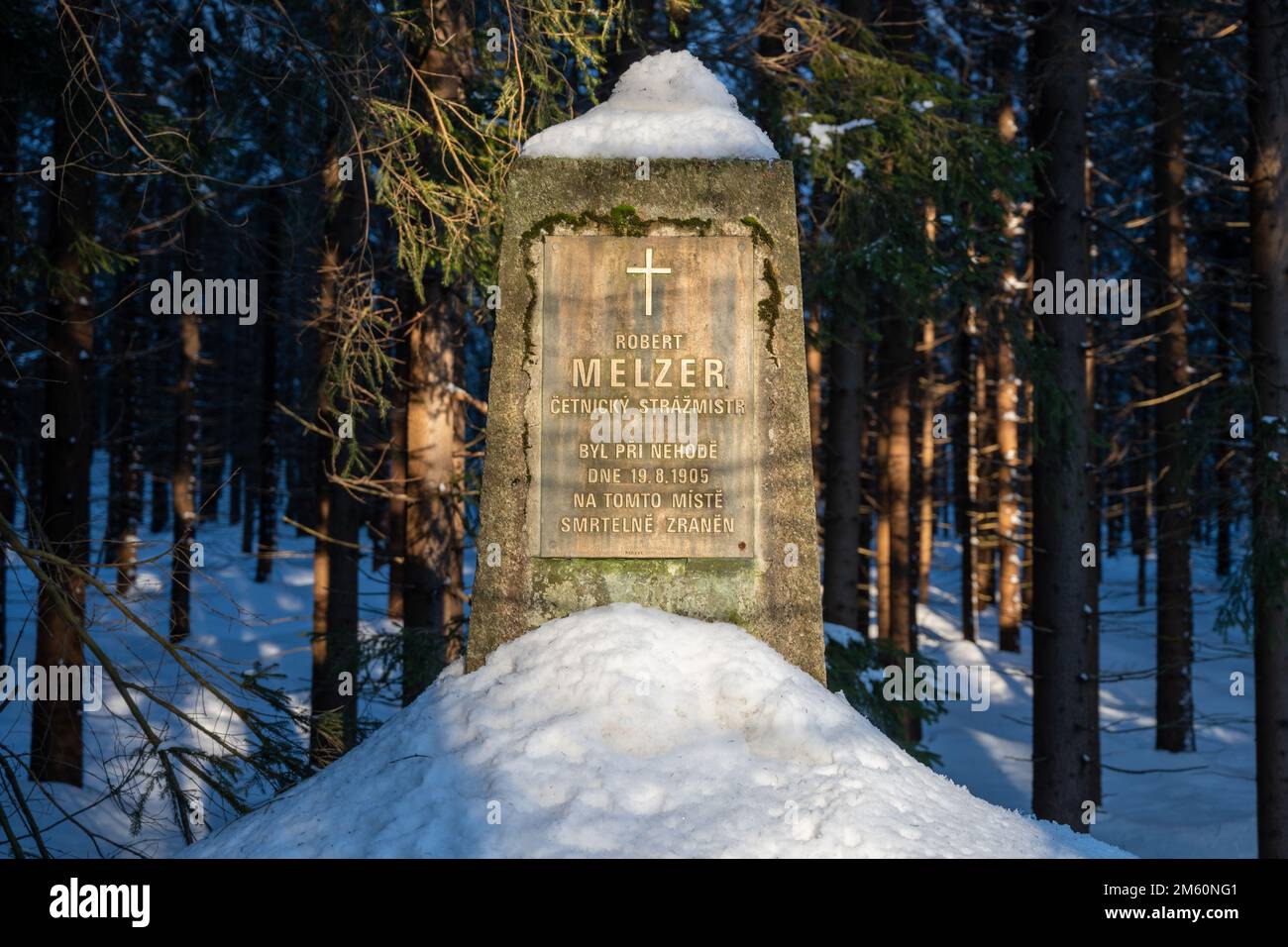 Stone memorial in the winter forest. Inscription: Warden Robert Melzer ...