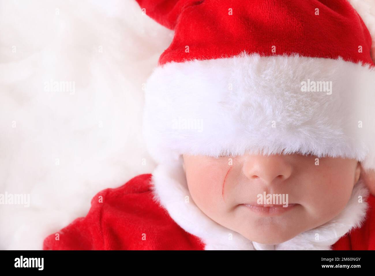 An infant wearing a Santa's hat that is covering his eyes Stock Photo ...