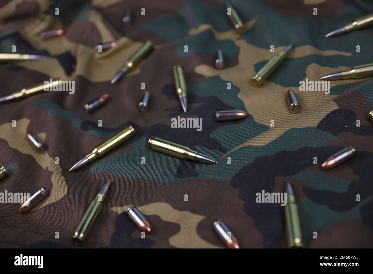 Many rifle bullets and cartridges on dark camouflage background ...