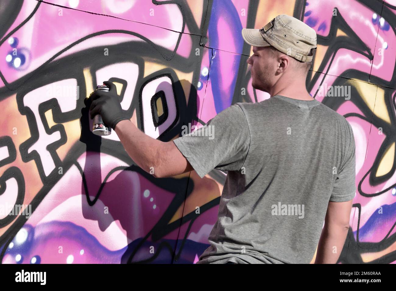 Young caucasian male graffiti artist drawing big street art painting in ...