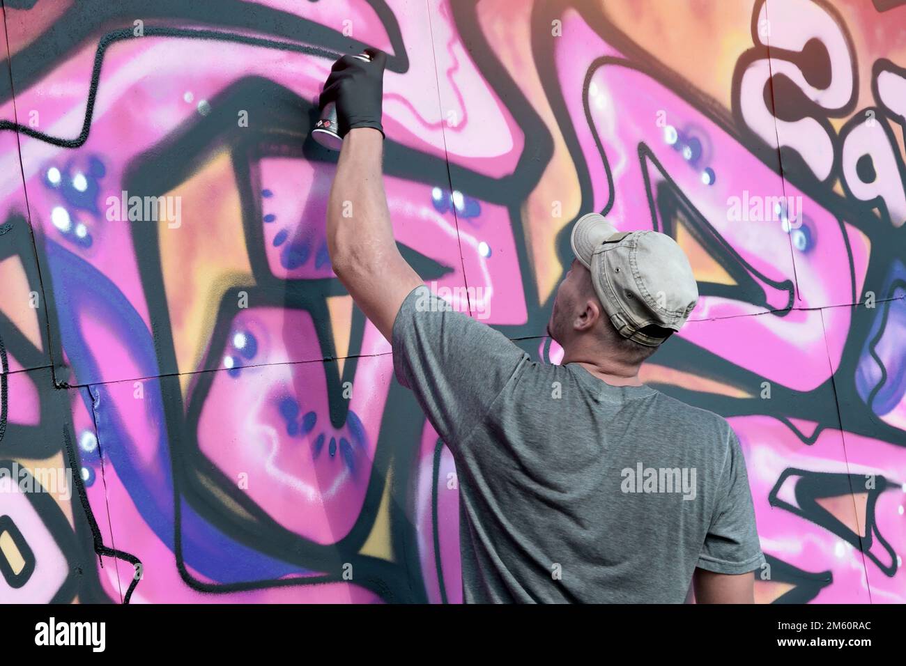 Young caucasian male graffiti artist drawing big street art painting in ...