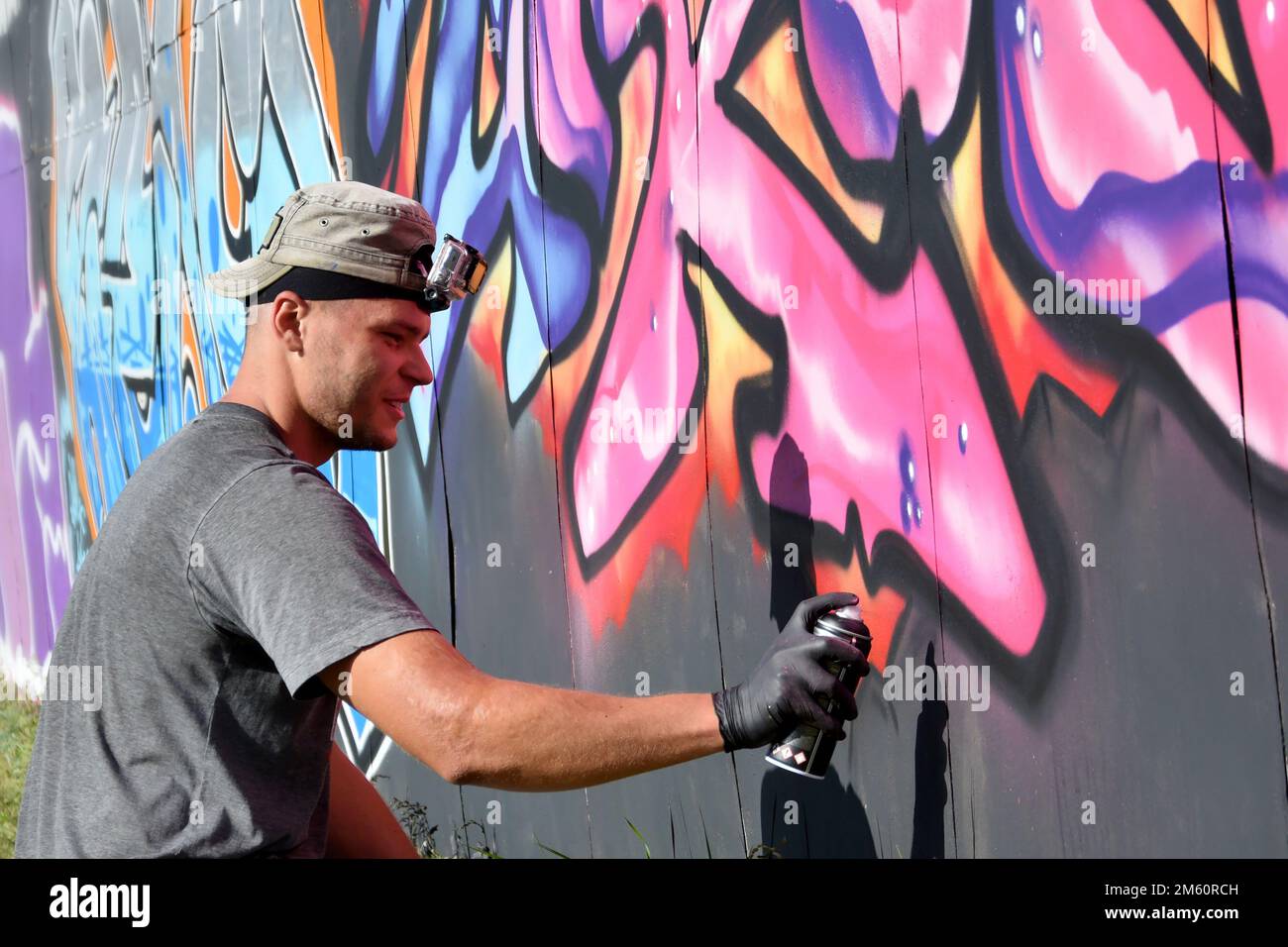 Young caucasian male graffiti artist drawing big street art painting in ...