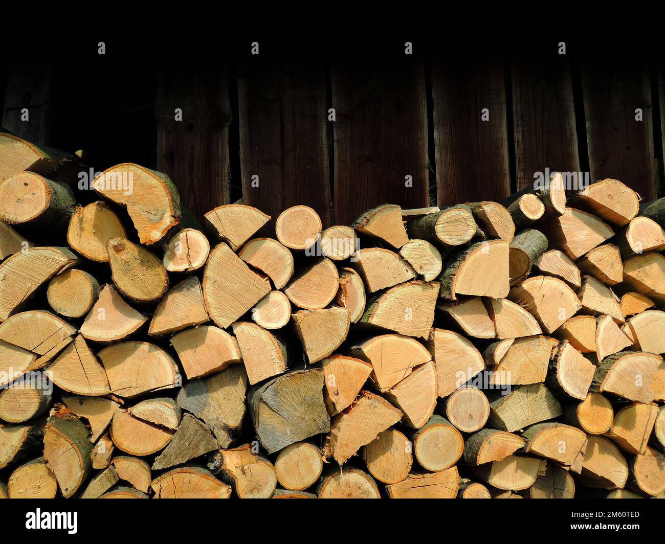 Whole, split in half and chopped oak firewood near the wall of old ...