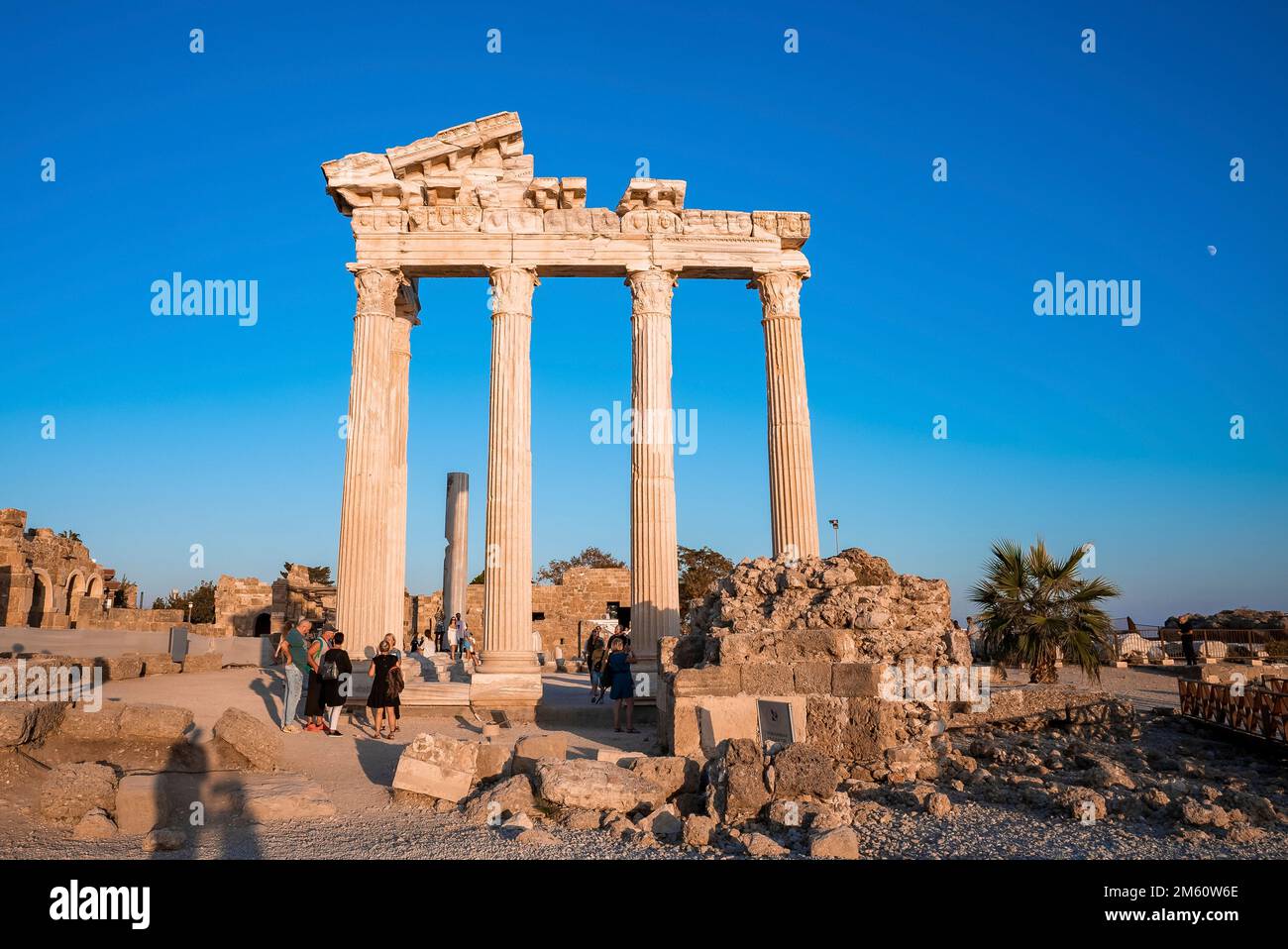 Tourists exploring old ruins of the Temple of Apollo on coastline at ...