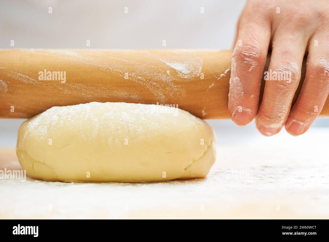 Rolling the dough with a rolling pin, bread making process Stock Photo ...