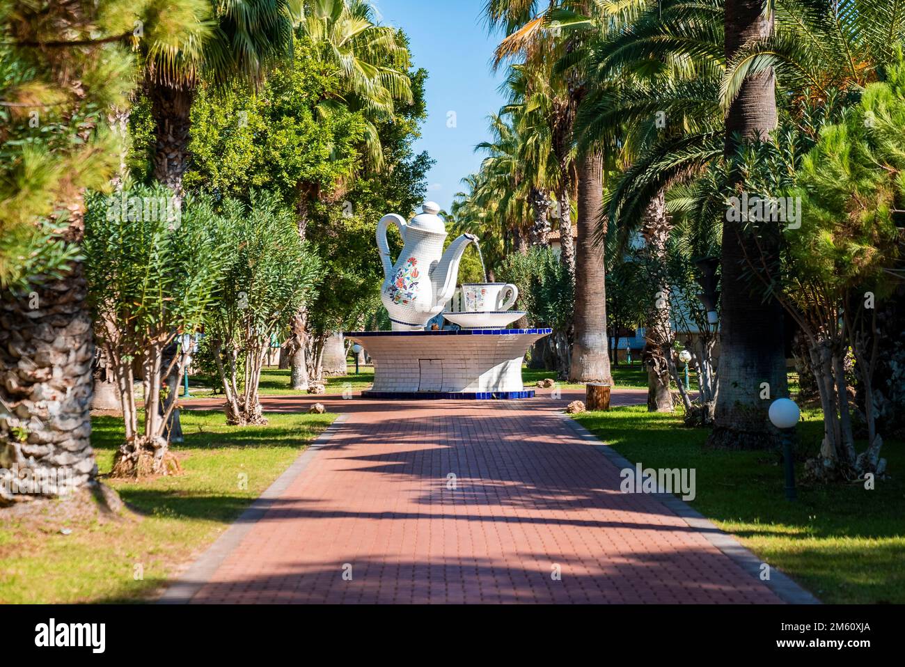 Sculpture of kettle pouring water in cup amidst trees in garden Stock ...
