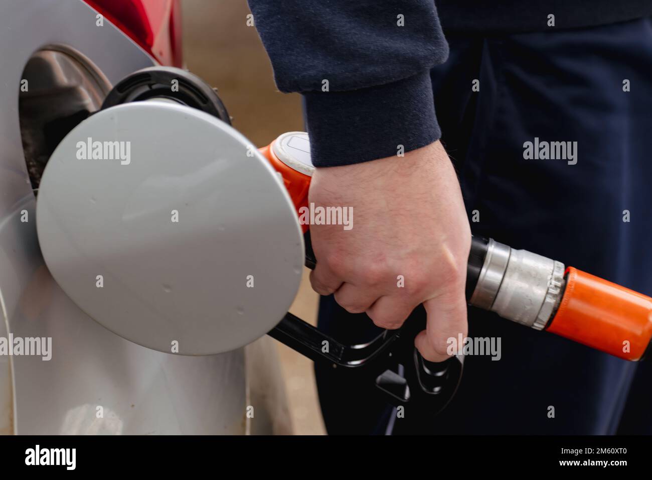 Man refueling a car in Europe with a pistol in his hand. Gas station ...