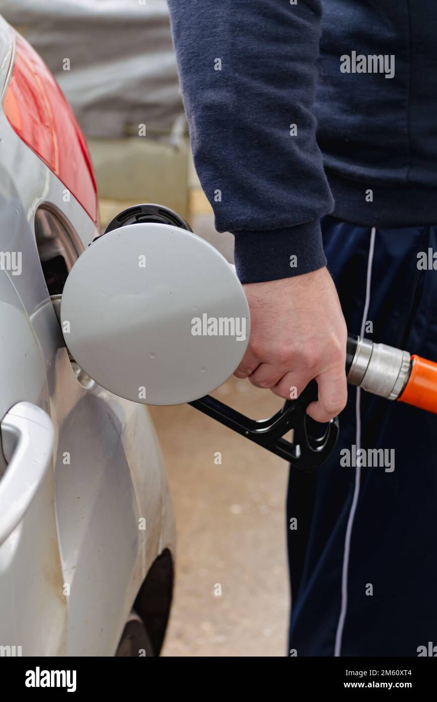 Man refueling a car in Europe with a pistol in his hand. Gas station ...