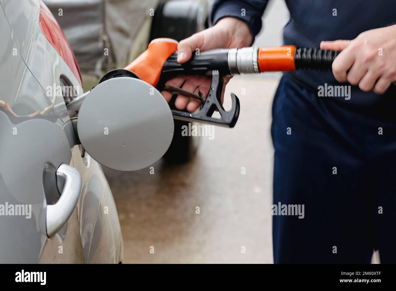 Man refueling a car in Europe with a pistol in his hand. Gas station ...