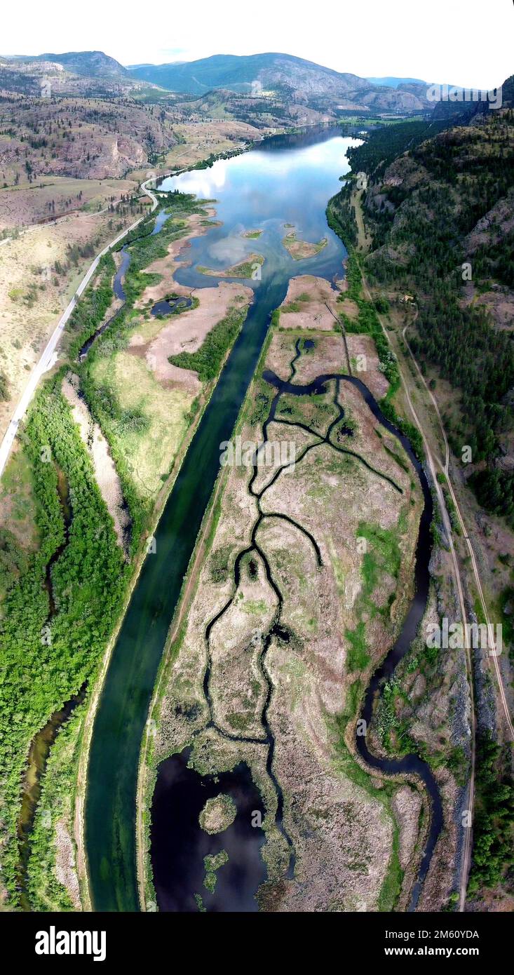 A vertical shot of a lake flowing in a field in the daylight Stock ...