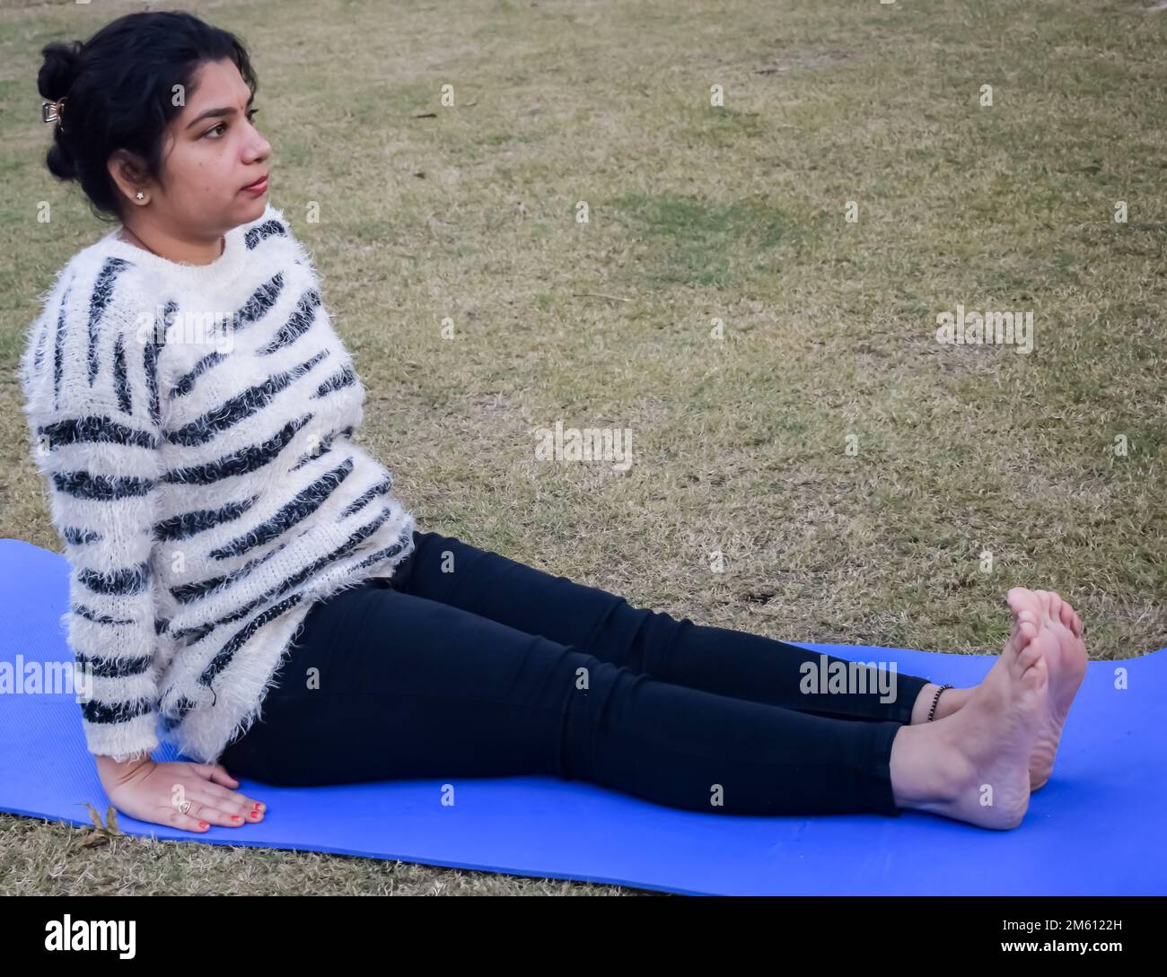 Young Indian woman practicing yoga outdoor in a park. Beautiful girl ...