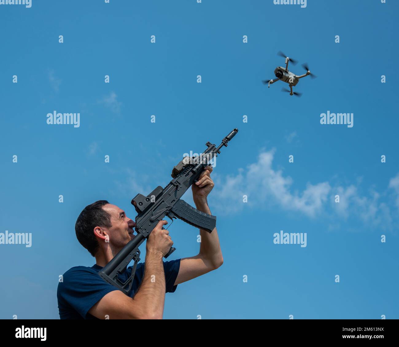 A man aims to shoot a rifle at a flying drone against a blue sky Stock ...