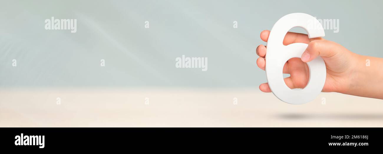 Number six in hand. Hand holding white number 6 on blurred background ...