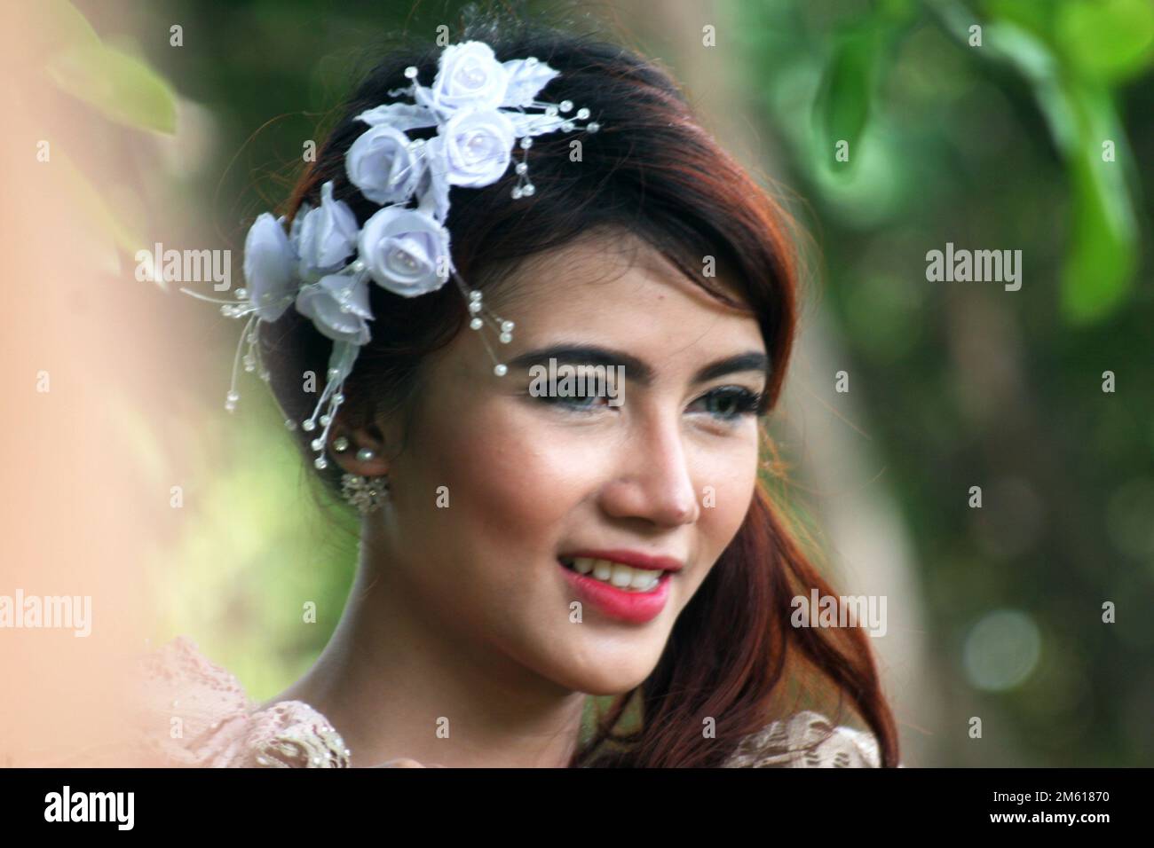 portrait of a smiling Indonesian woman. she wears white flower ...