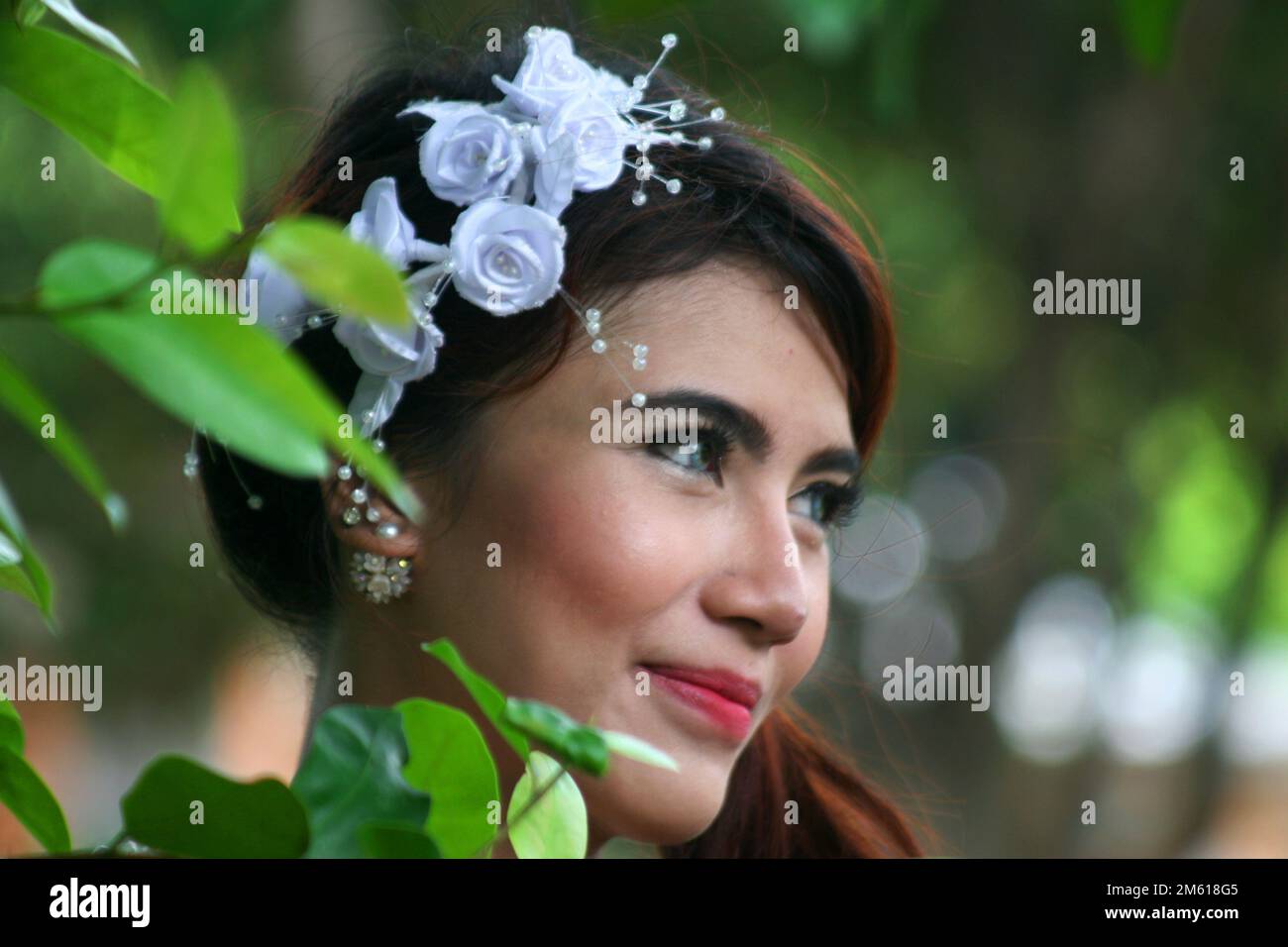 portrait of a smiling Indonesian woman. she wears white flower ...