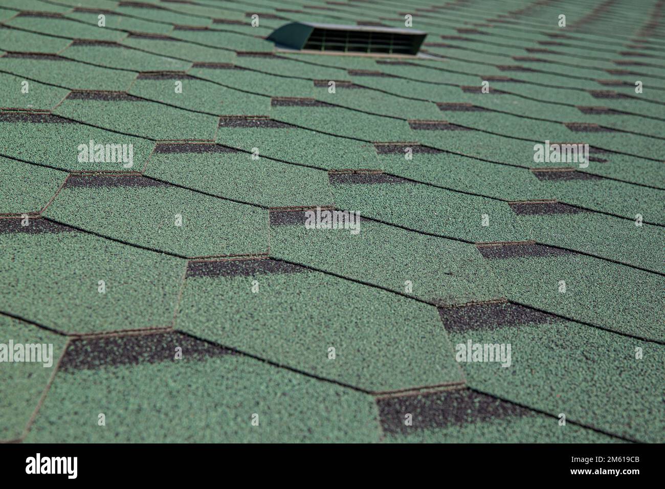 Roofing made of green soft bitumen tiles on a hipped roof of a house ...