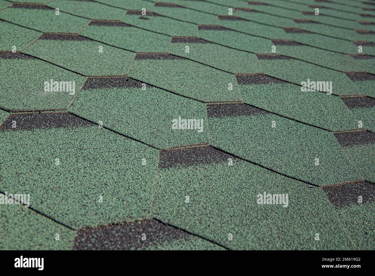 Roofing made of green soft bitumen tiles on a hipped roof of a house ...