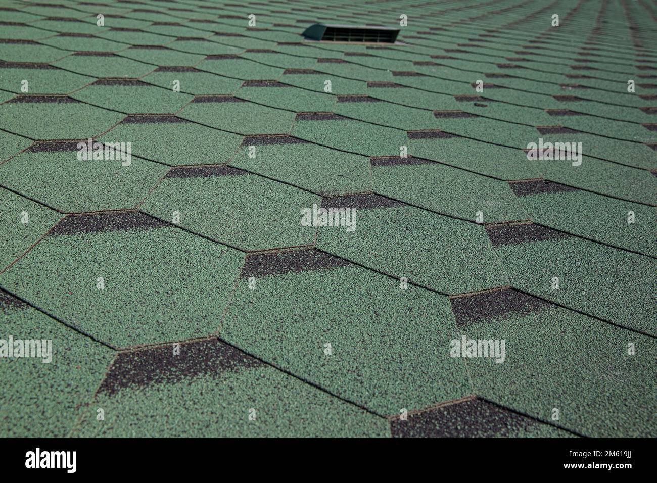 Roofing made of green soft bitumen tiles on a hipped roof of a house ...