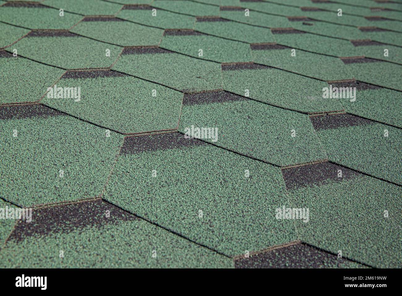 Roofing made of green soft bitumen tiles on a hipped roof of a house ...