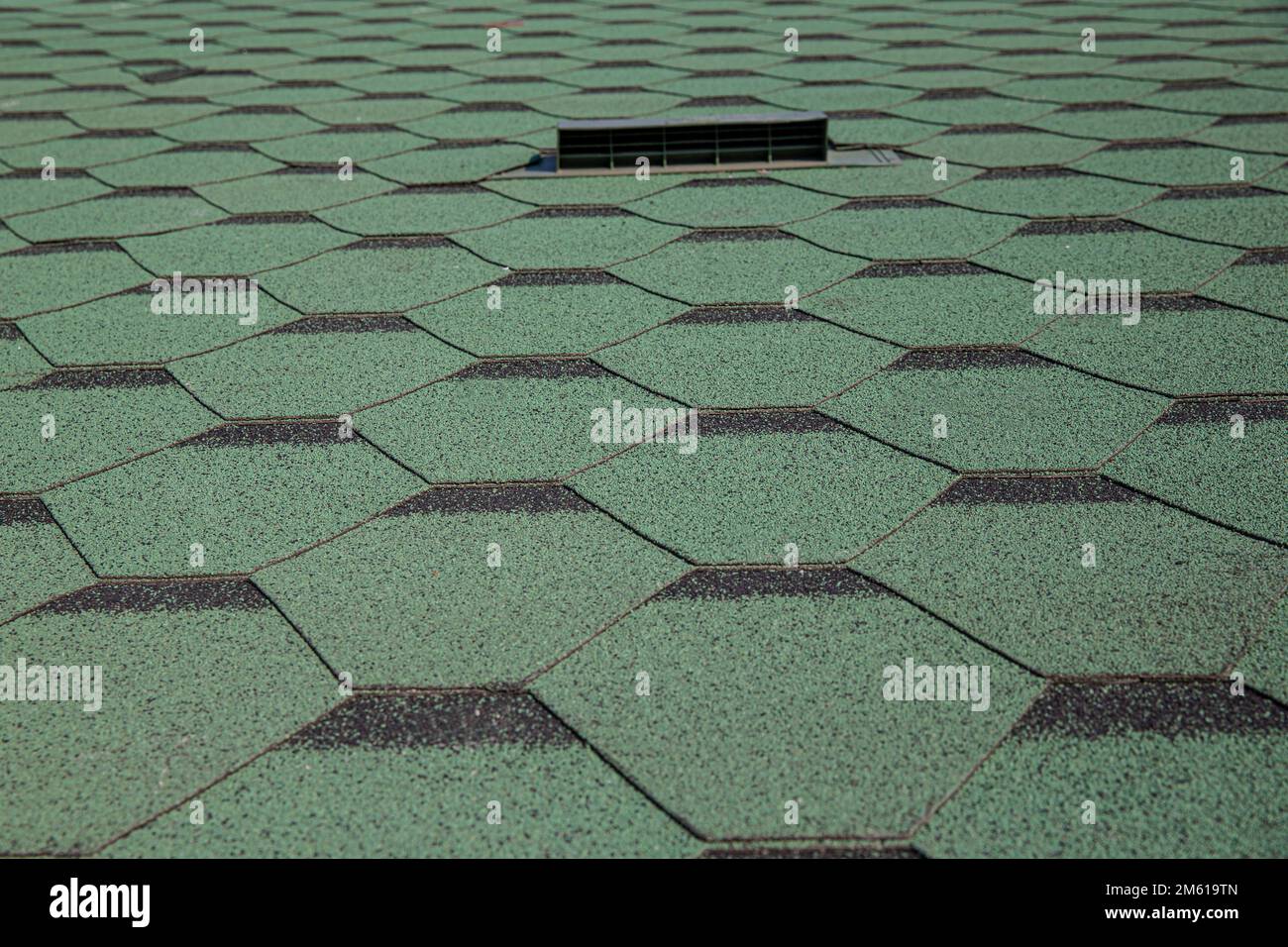 Roofing made of green soft bitumen tiles on a hipped roof of a house ...