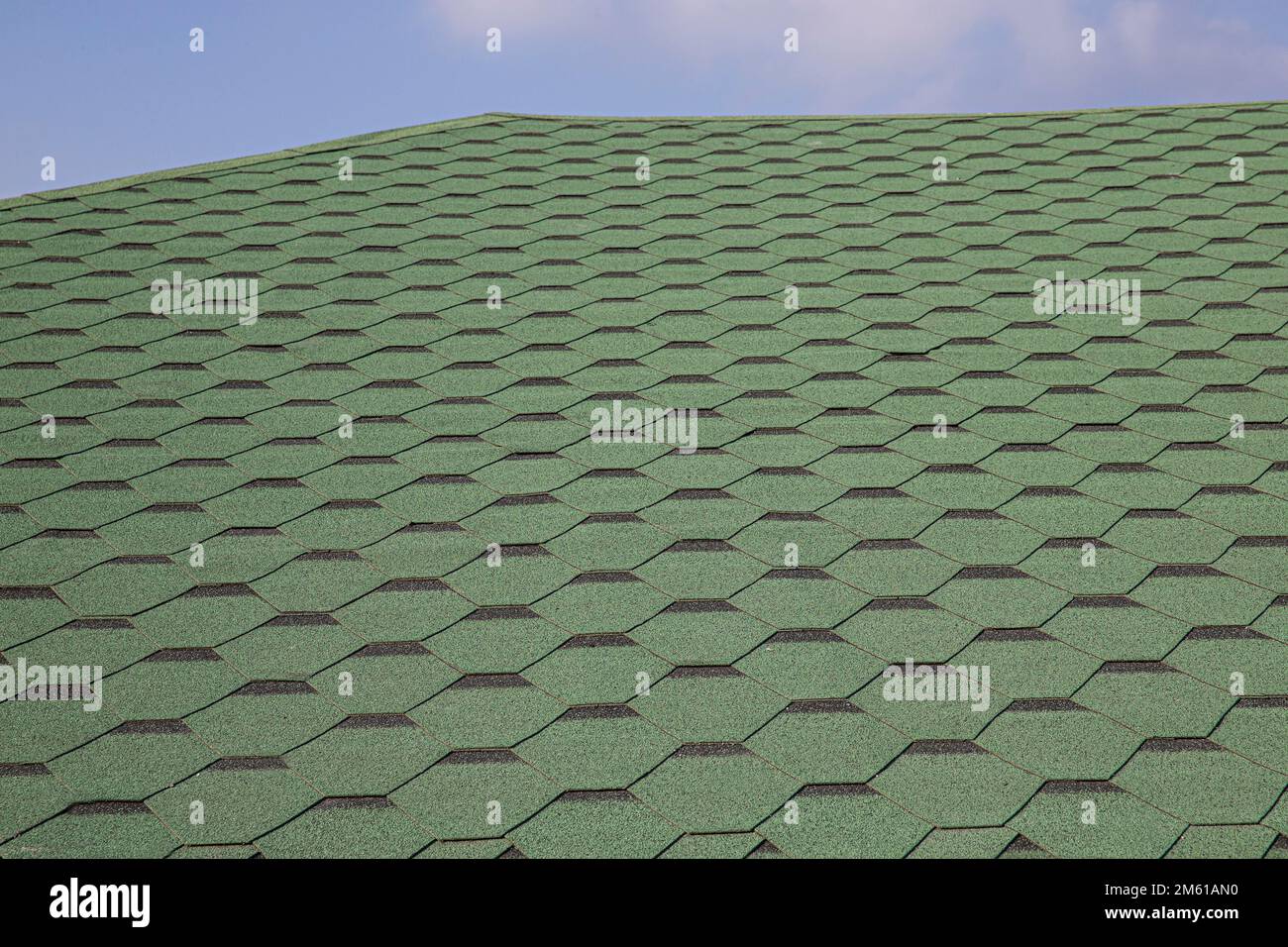 Roofing made of green soft bitumen tiles on a hipped roof of a house ...