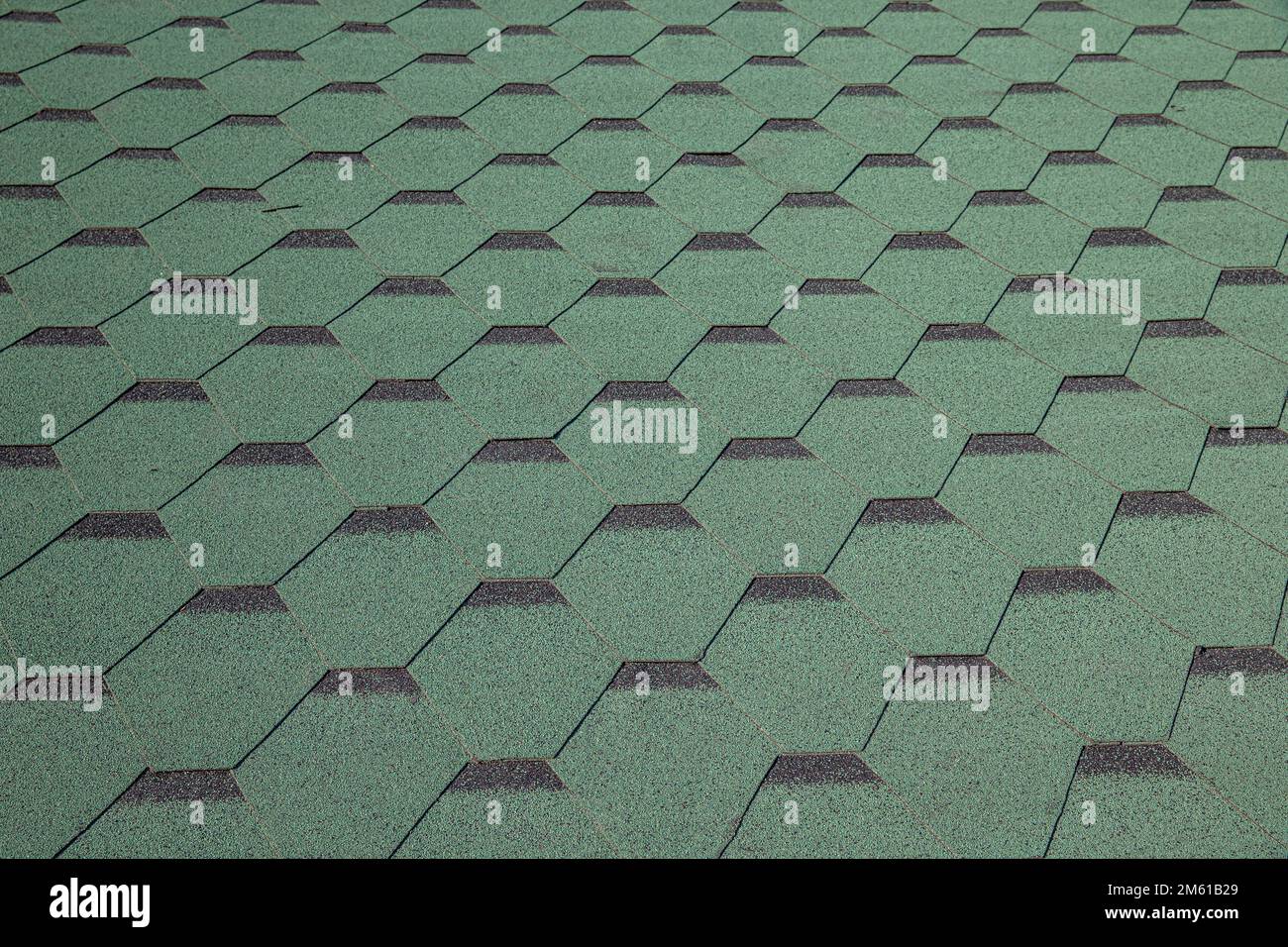 Roofing made of green soft bitumen tiles on a hipped roof of a house ...