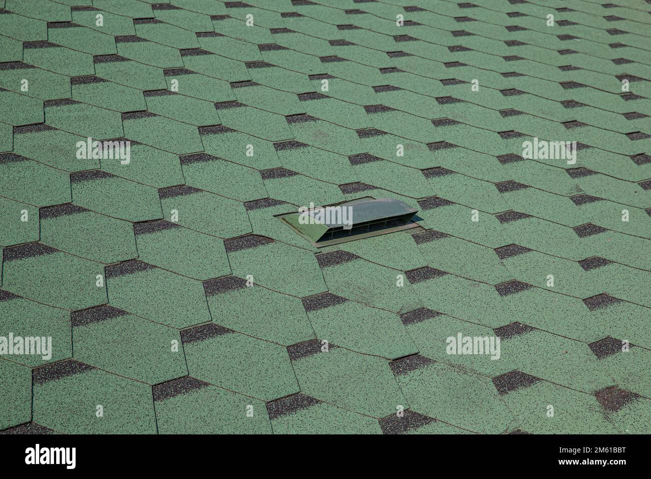 Roofing made of green soft bitumen tiles on a hipped roof of a house ...