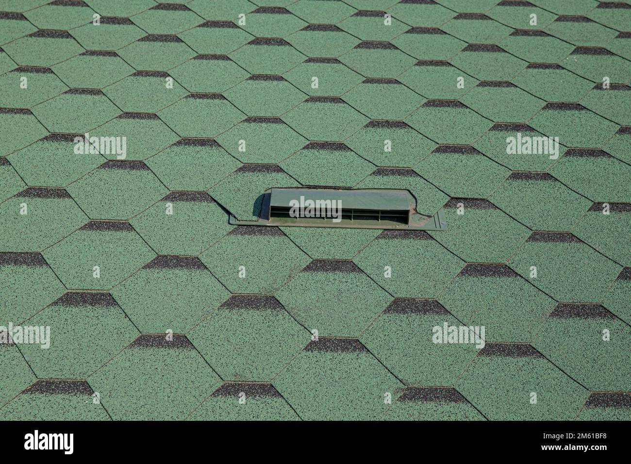 Roofing made of green soft bitumen tiles on a hipped roof of a house ...