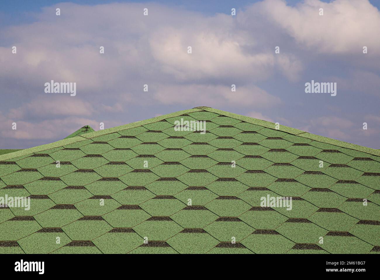 Roofing made of green soft bitumen tiles on a hipped roof of a house ...