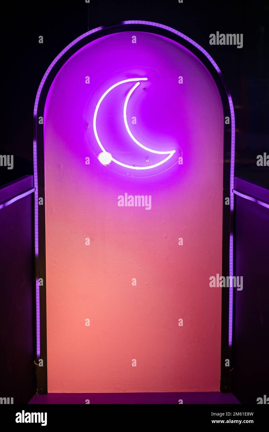 A crescent moon-shaped neon symbol on a gradient purple-pink background ...
