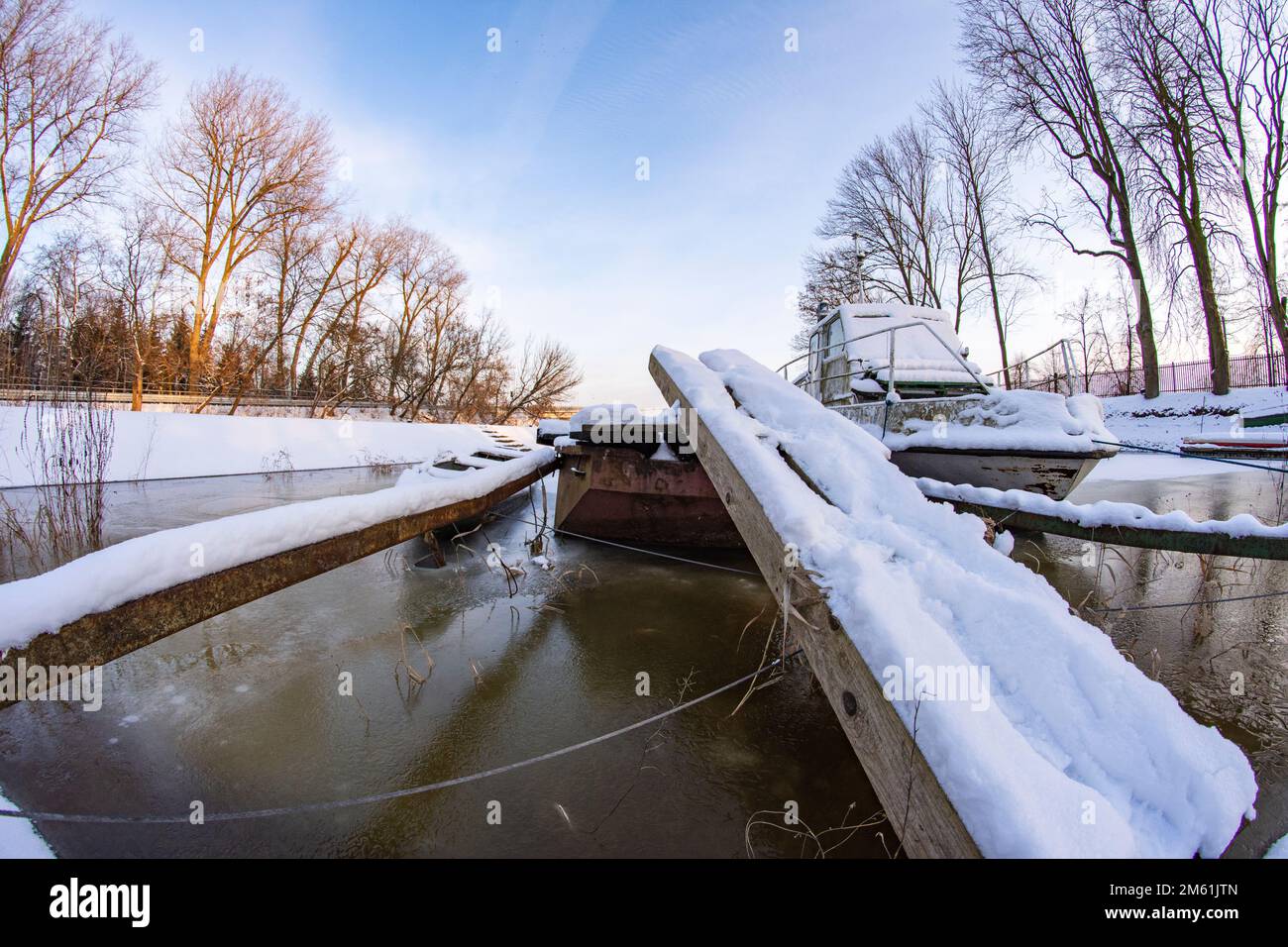 Yacht and jetty in a winter harbor covered in ice and snow, bridge and ...