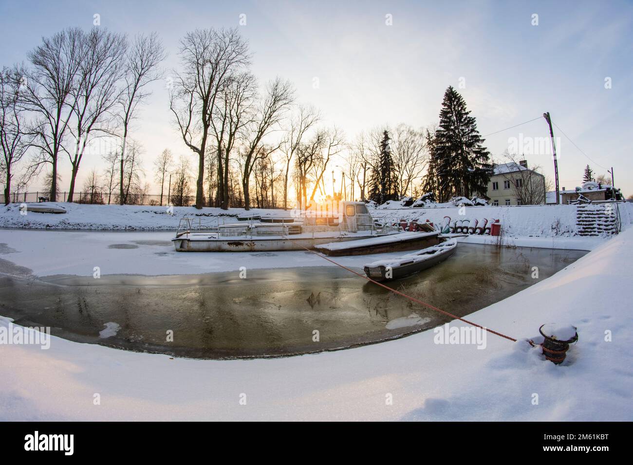 Yacht and jetty in a winter harbor covered in ice and snow, bridge and ...