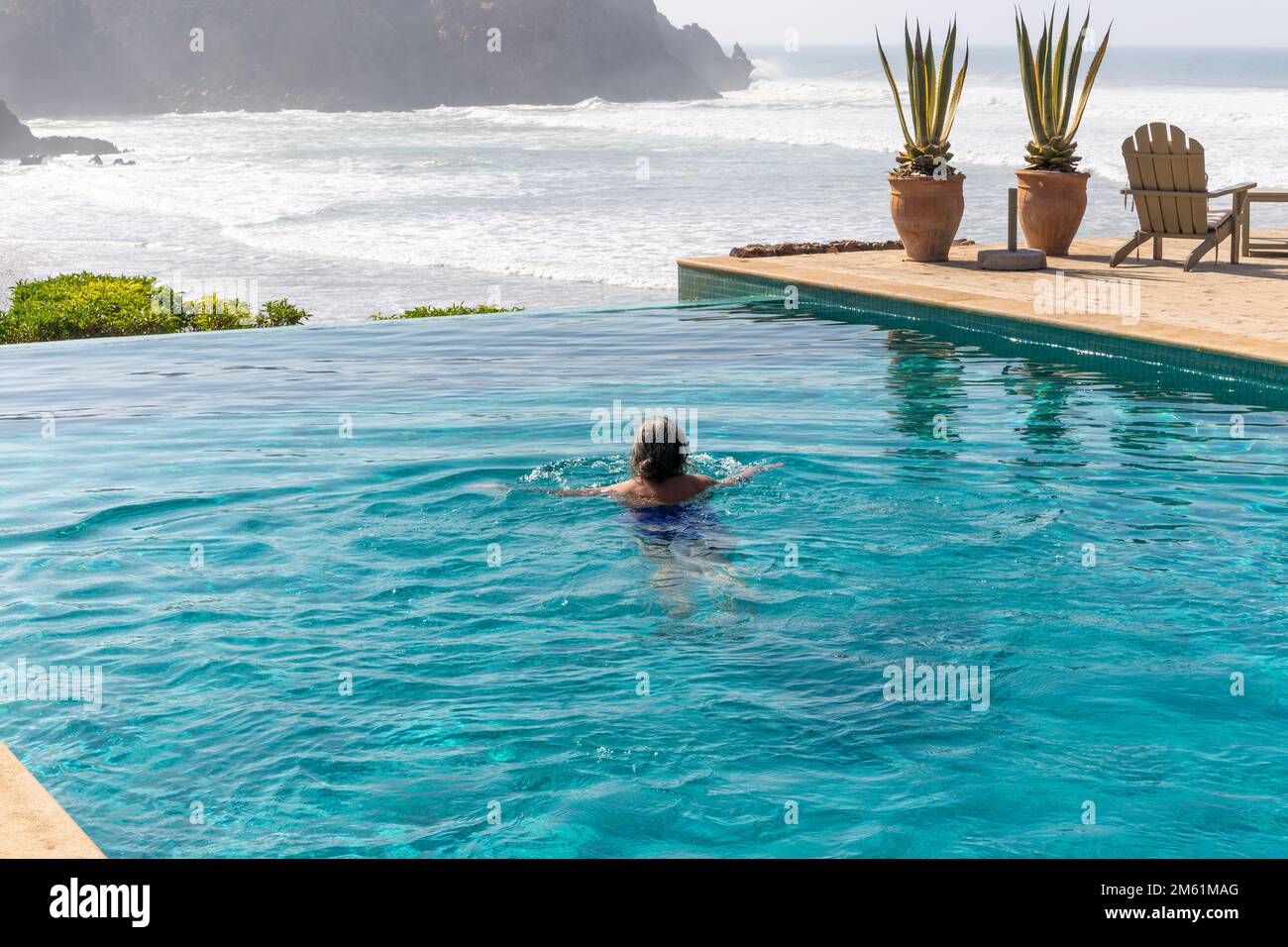 Woman swimming infinity pool by Atlantic Ocean, Hotel auberge Dar ...