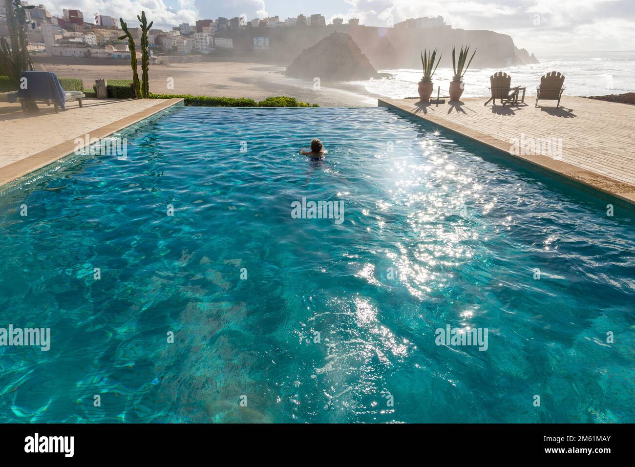 Woman swimming infinity pool by Atlantic Ocean, Hotel auberge Dar ...